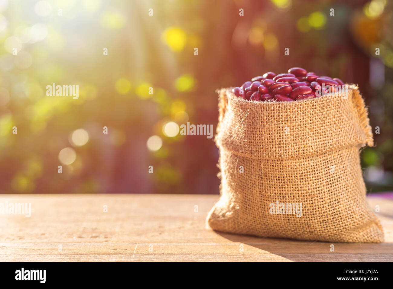 Close up red bean in small brown sack on wooden table. Outdoor shooting ...