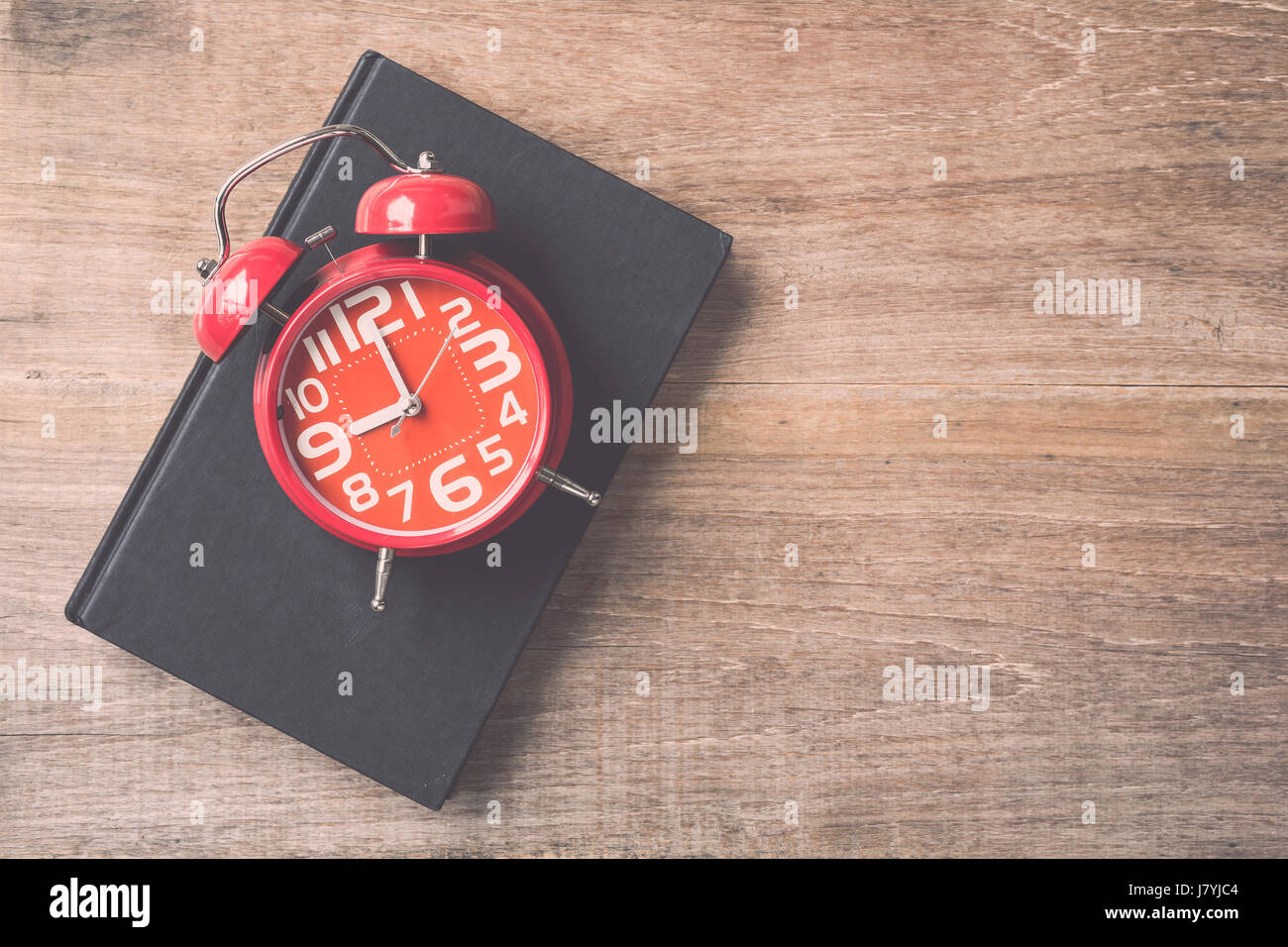 Top view book and red clock on wooden plank background. Time for ...
