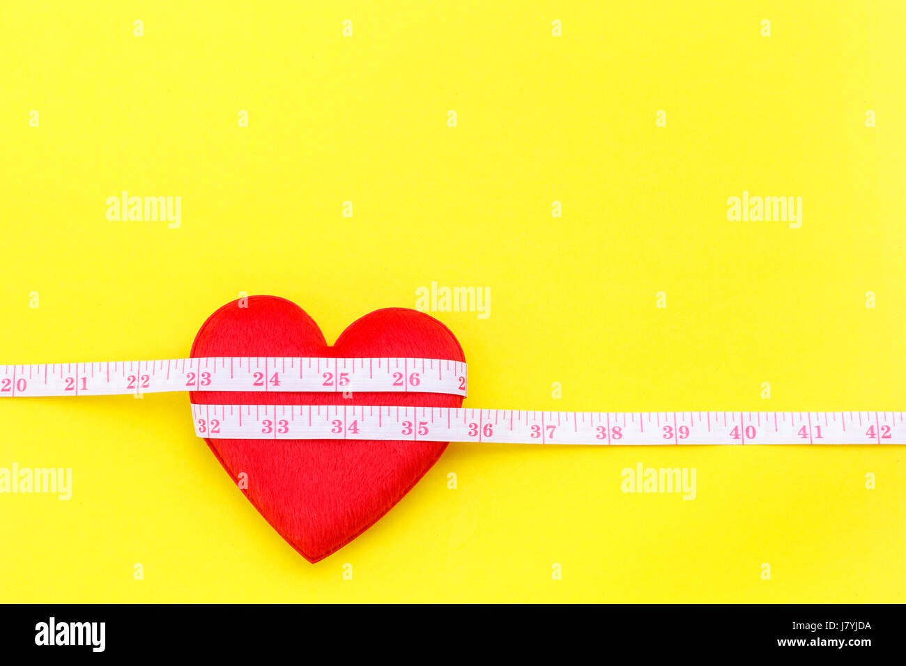 Top view red heart shape and white measurement tape on yellow ...