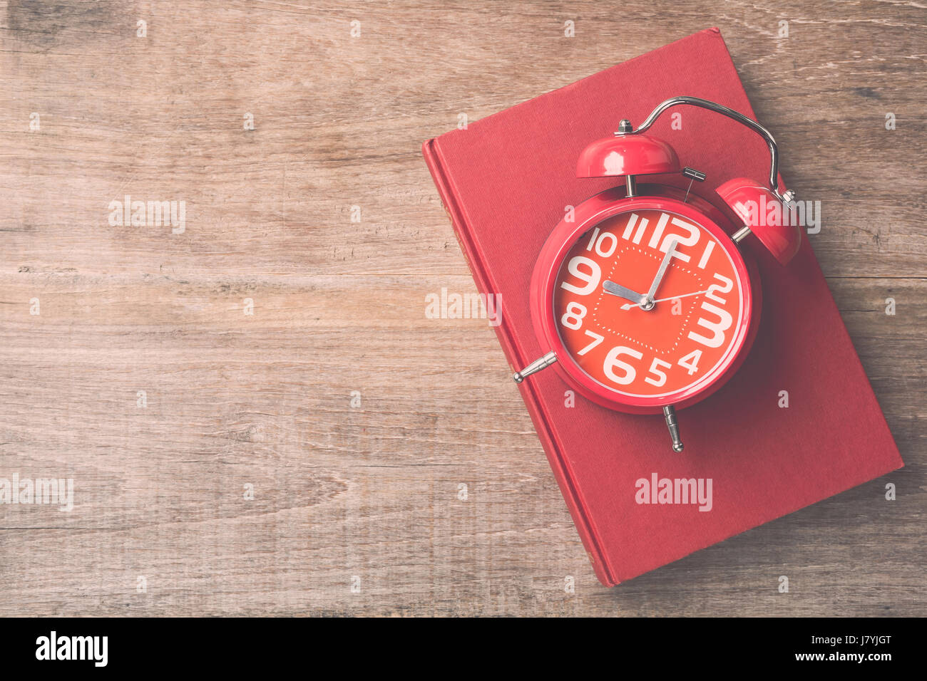 Top view book and red clock on wooden plank background. Time for ...
