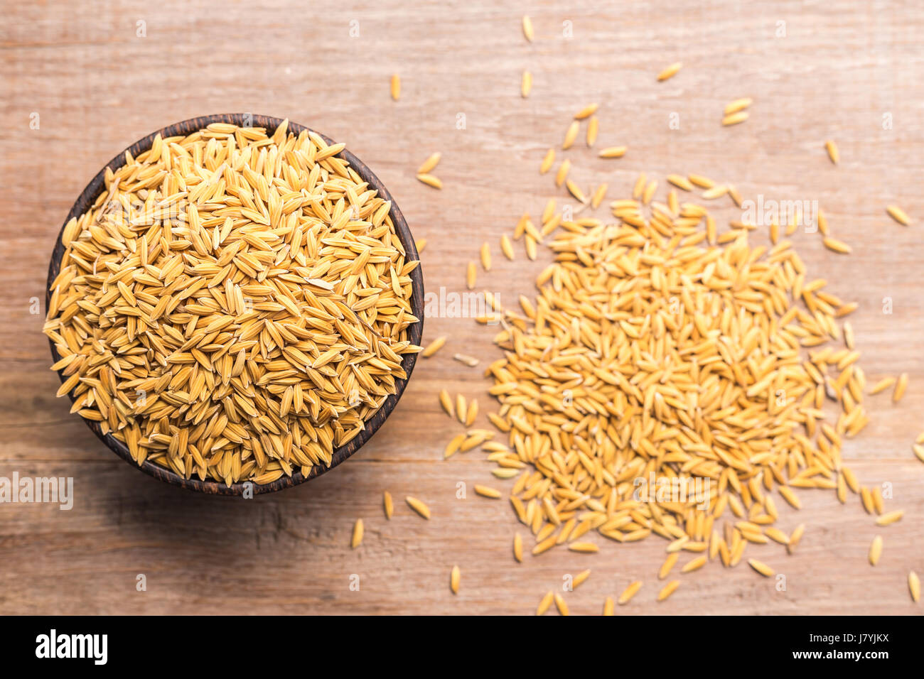 Top view Thai yellow paddy rice in wooden bowl put on wooden plank ...
