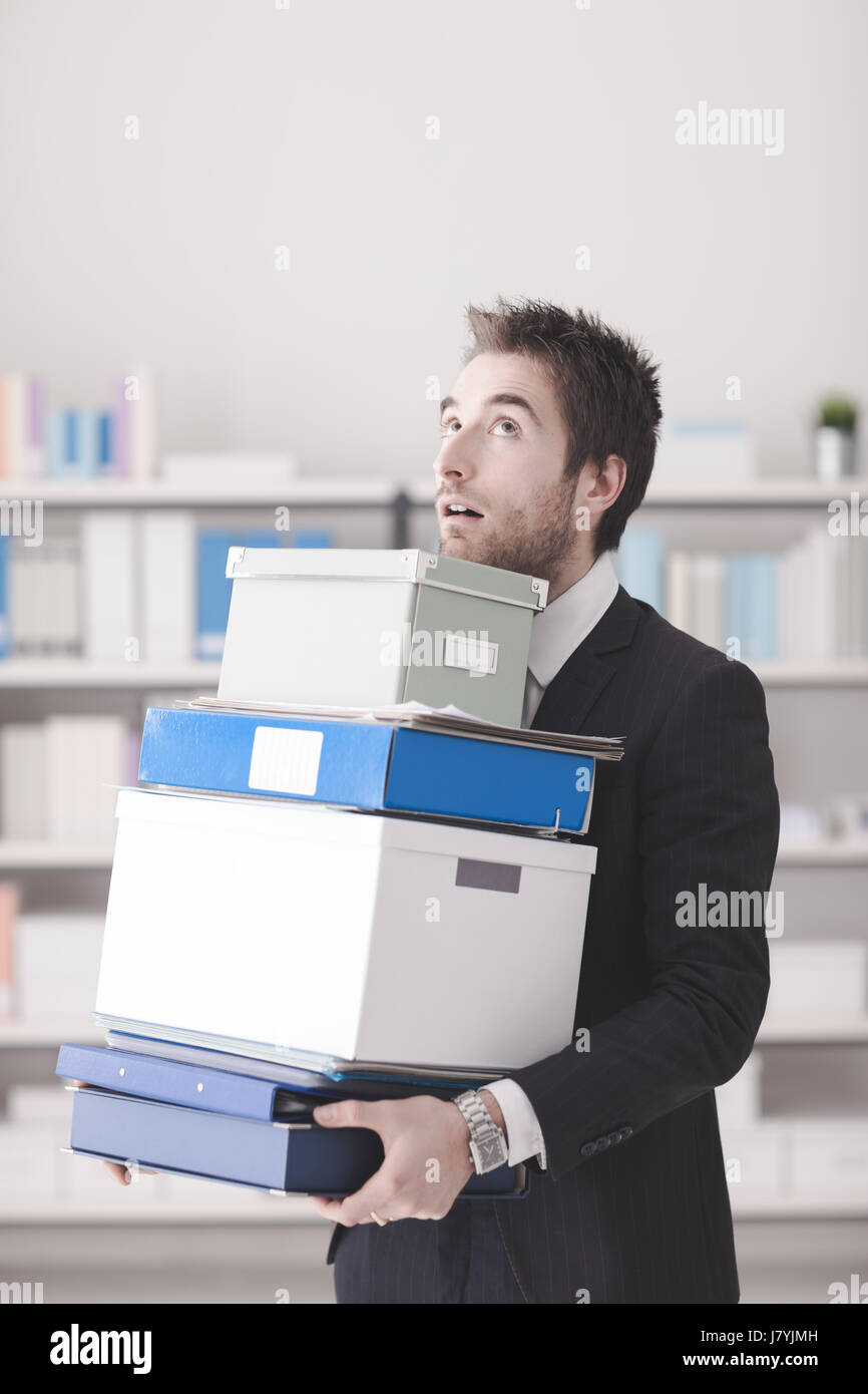 Disappointed businessman carrying heavy boxes and folders in the office ...