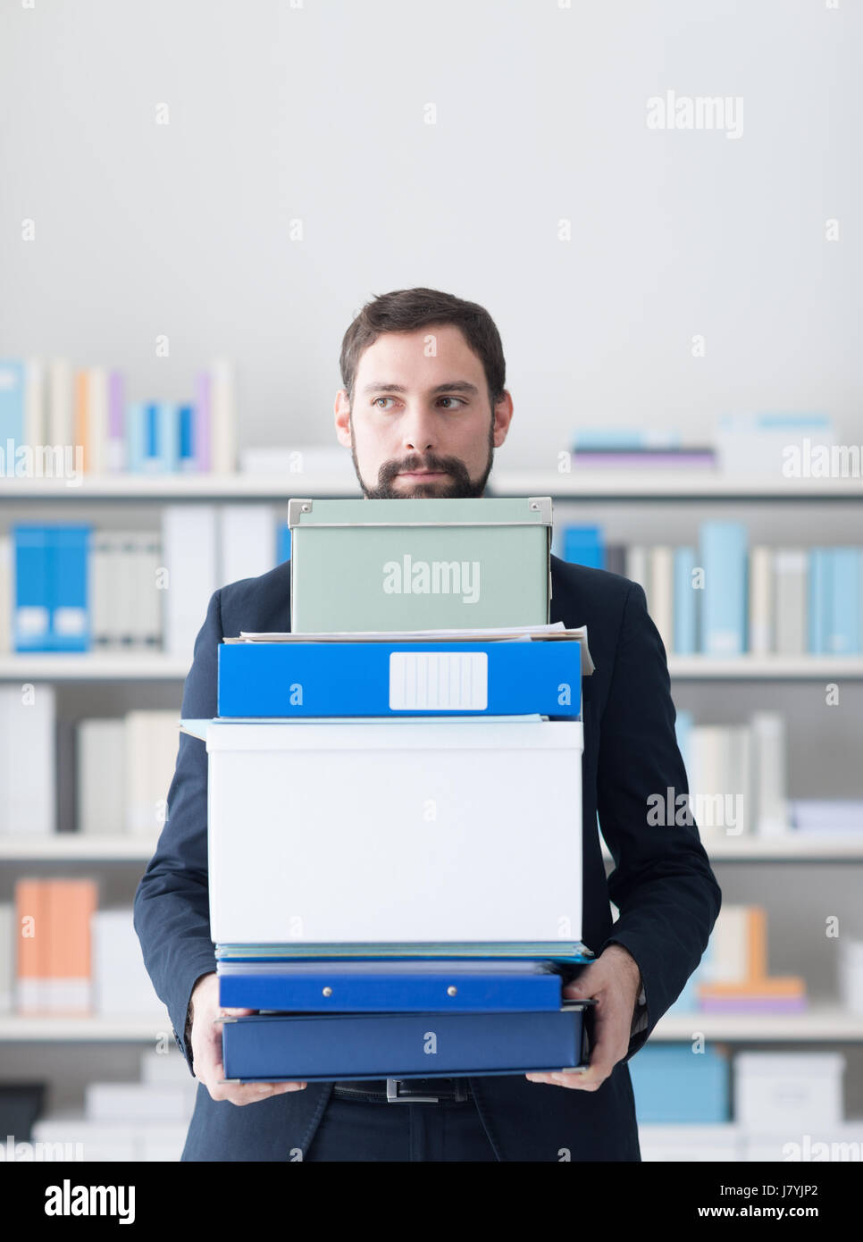 Disappointed businessman carrying heavy boxes and folders in the office ...