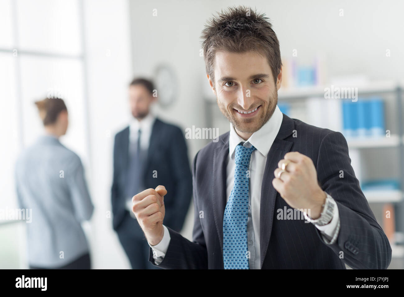 Cheerful young businessman rejoycing with raised fists, satisfaction ...