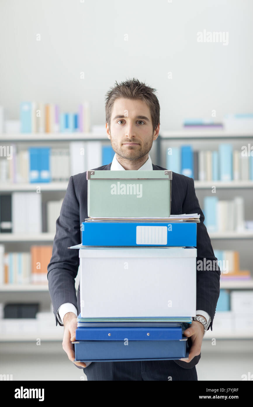 Young businessman carrying stack of boxes in office at late night Stock ...