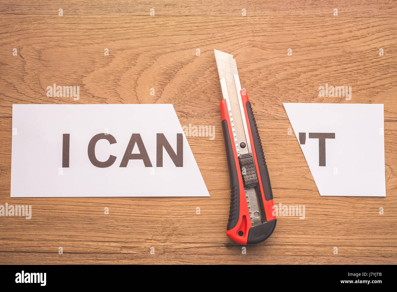 Top view red cutter blade cutting word "I CAN'T" in white paper on ...
