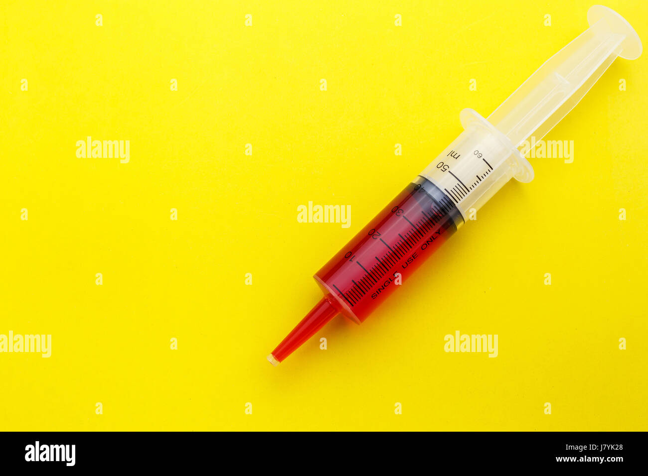 Top view of clear syringe with red drug on yellow background Stock ...