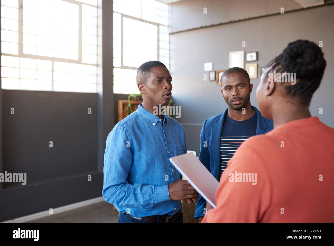 Focused African work colleagues talking business together in an office ...