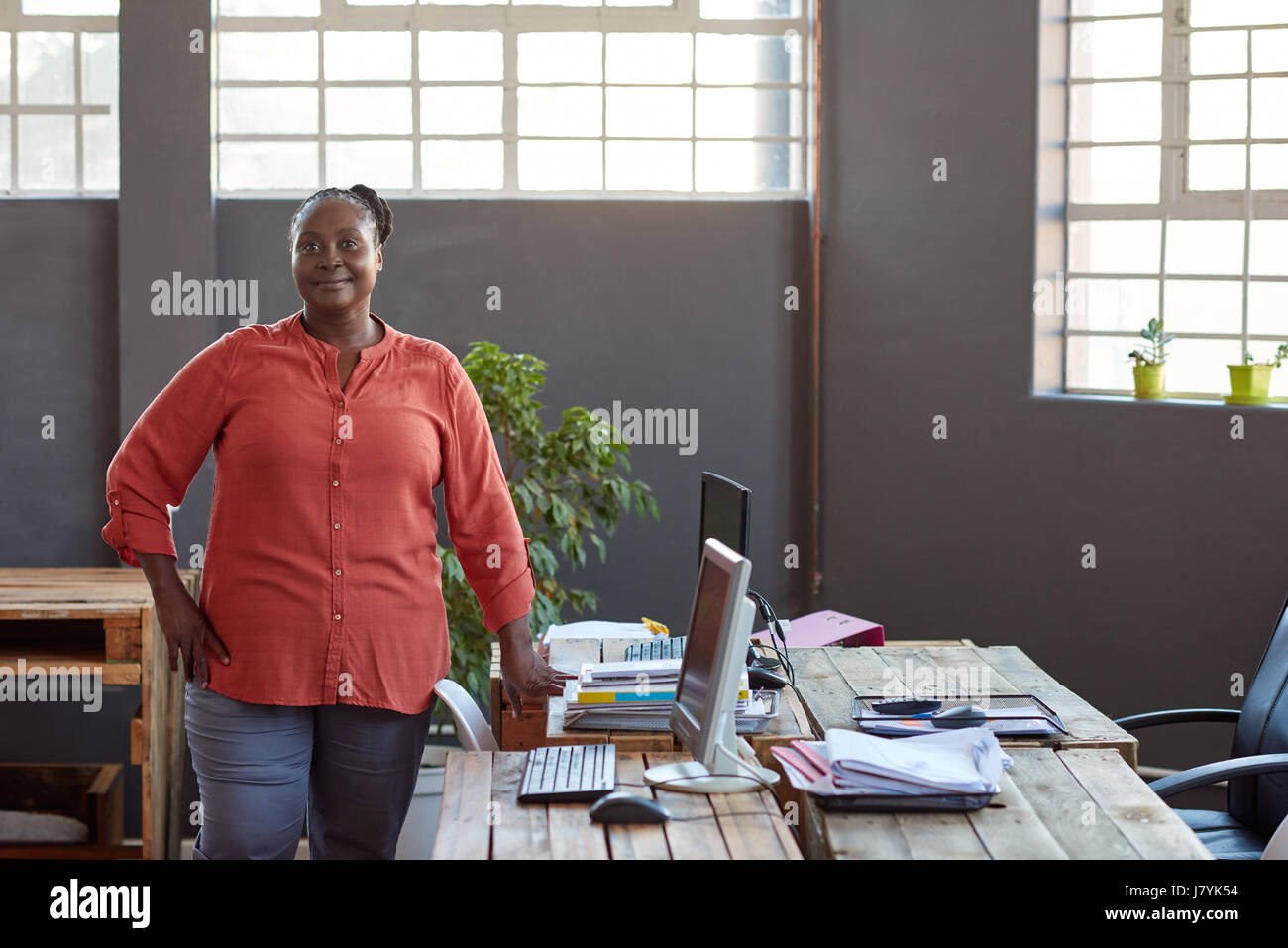 Smiling African businesswoman standing at her desk in an office Stock ...