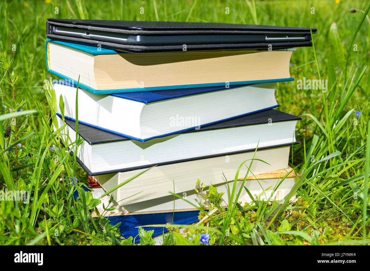 Pile of various books plus tablet in the fresh green grass Stock Photo ...