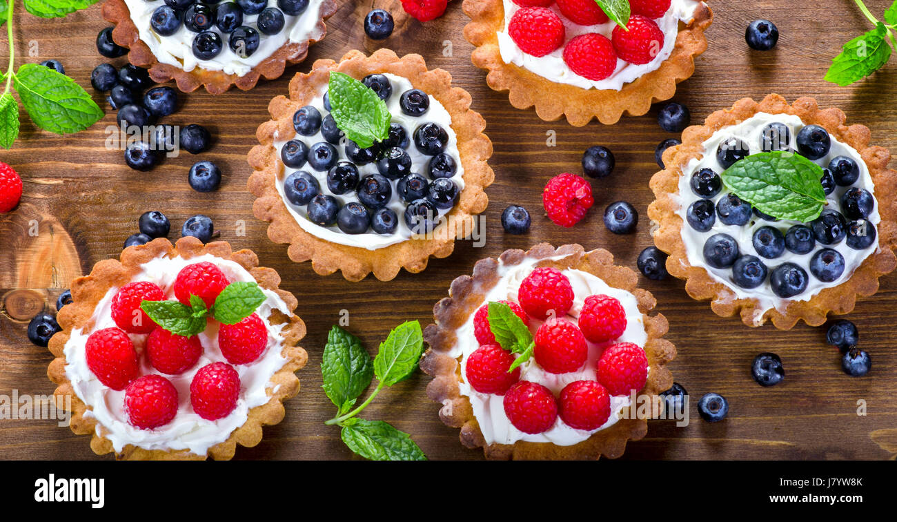 Sweet tarts with berries on wooden table. Banner. Flat lay Stock Photo ...