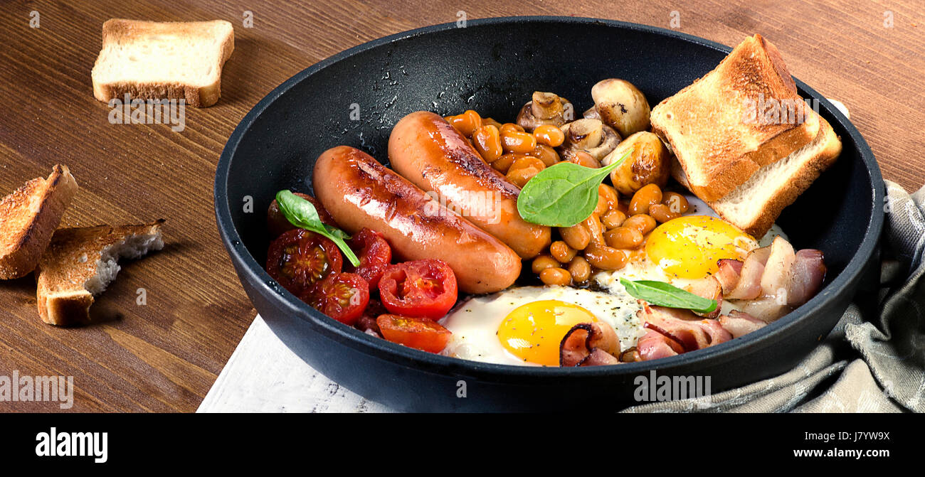 Full English breakfast with fried eggs, sausages, bacon, beans, toasts ...