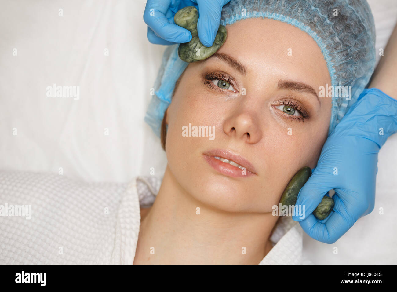 Beauty salon. Spa. Anti-aging facial massage with jade stones. Gua sha. Aesthetic facial ...