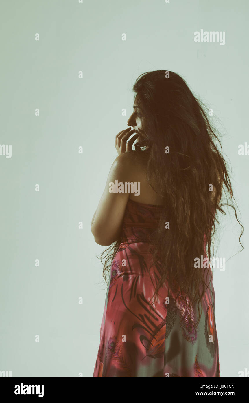 Rear view of a scared young woman looking away hand touching face Stock ...