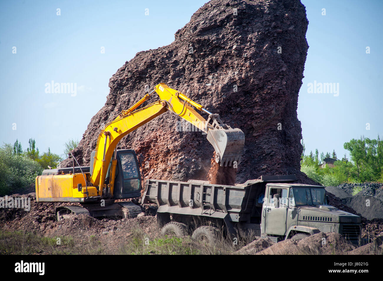 Excavator loading dumper truck with sand at a sand quarry Stock Photo ...