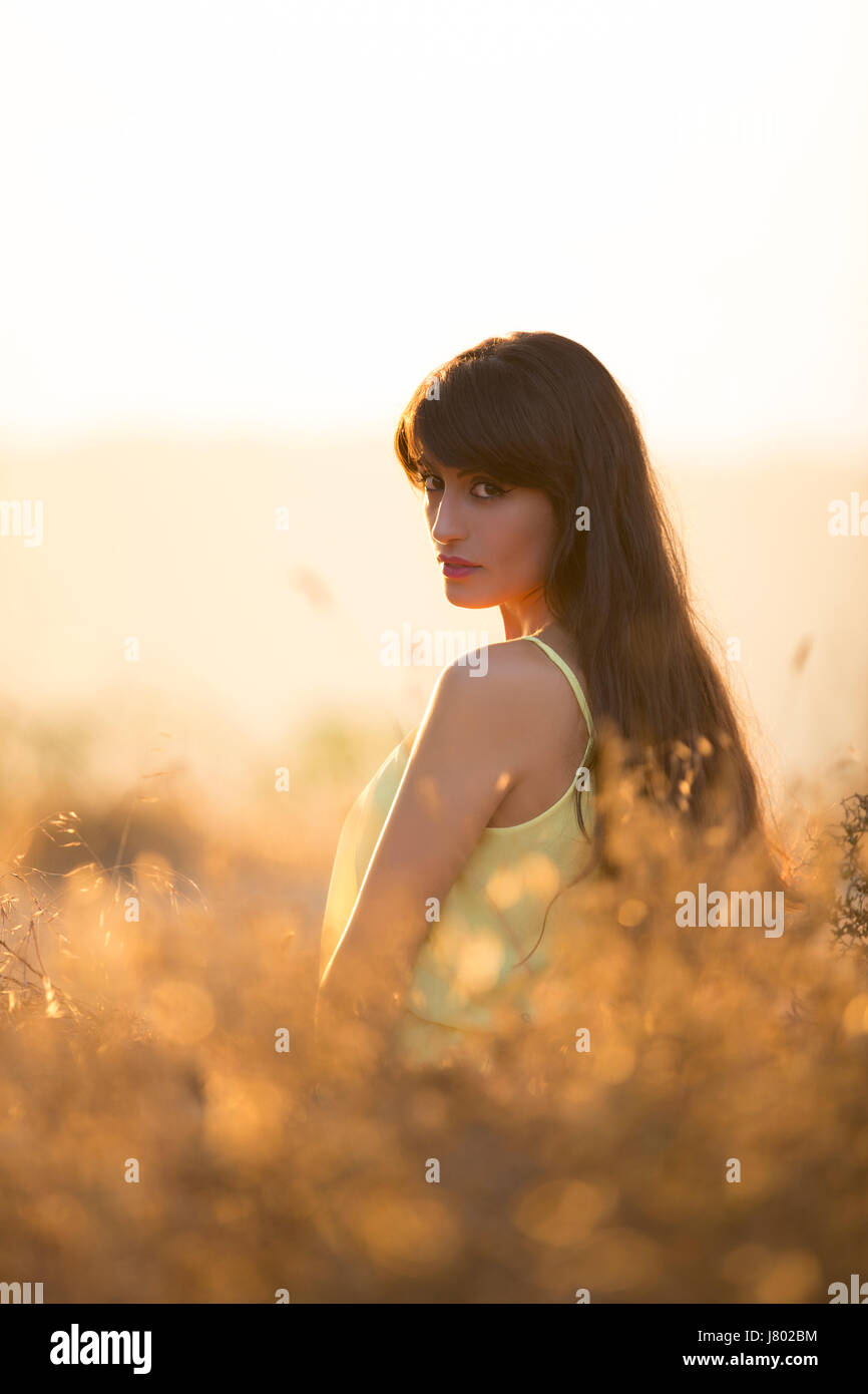 Beautiful young woman looking over shoulder at sunset Stock Photo - Alamy