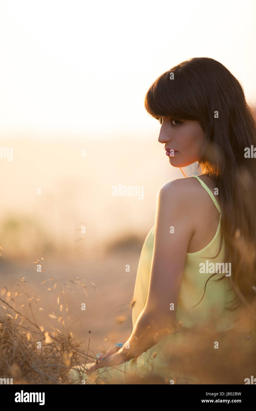 Beautiful woman looking over shoulder outdoors at sunset Stock Photo ...
