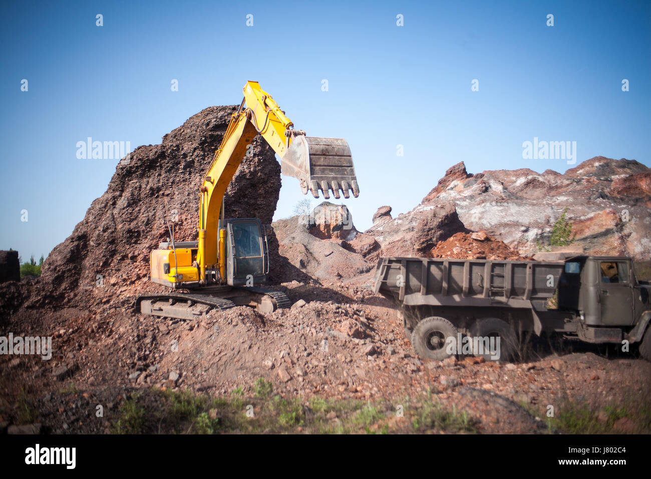 Excavator loading dumper truck with sand at a sand quarry Stock Photo ...