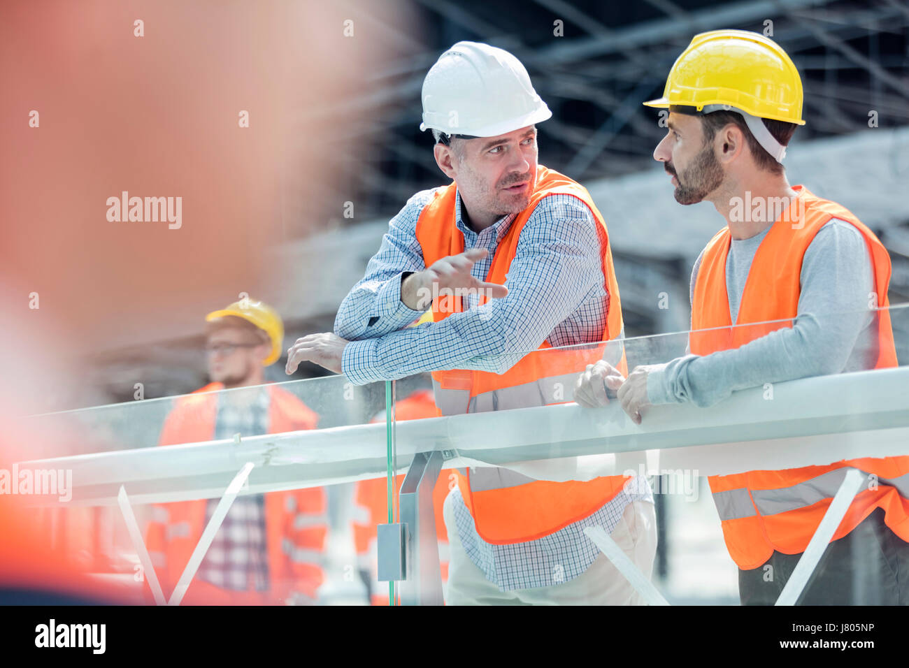 Male foreman and construction worker talking at construction site Stock ...