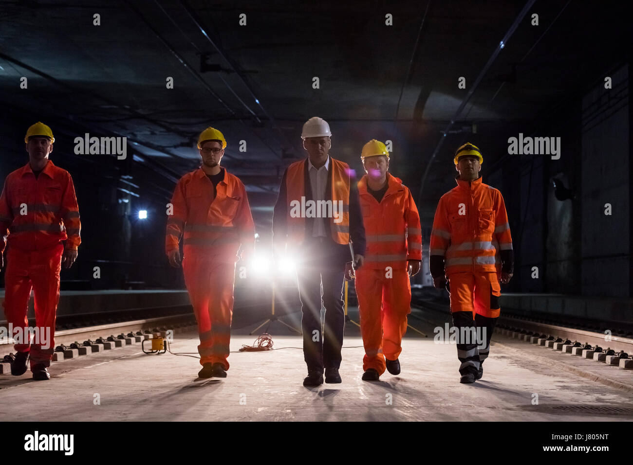 Male foreman and construction workers walking in dark construction site ...