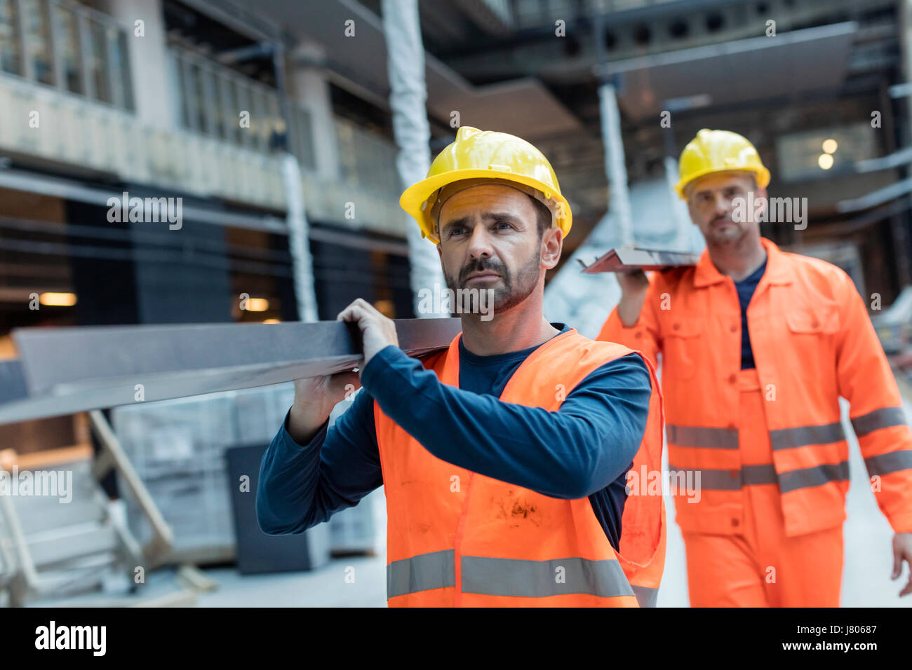 Construction workers carrying metal at construction site Stock Photo ...