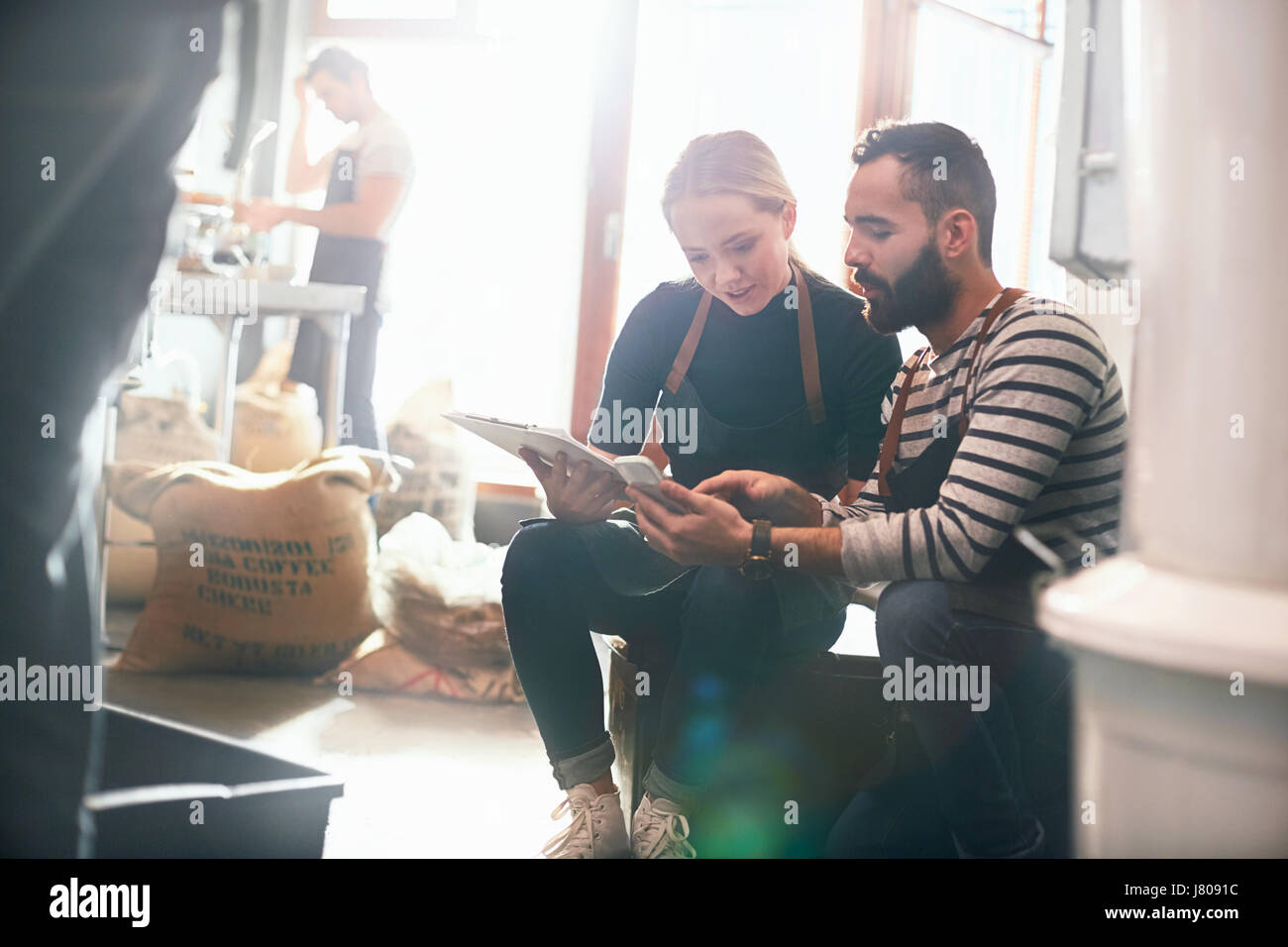 Coffee roasters meeting, looking at clipboard and cell phone Stock ...