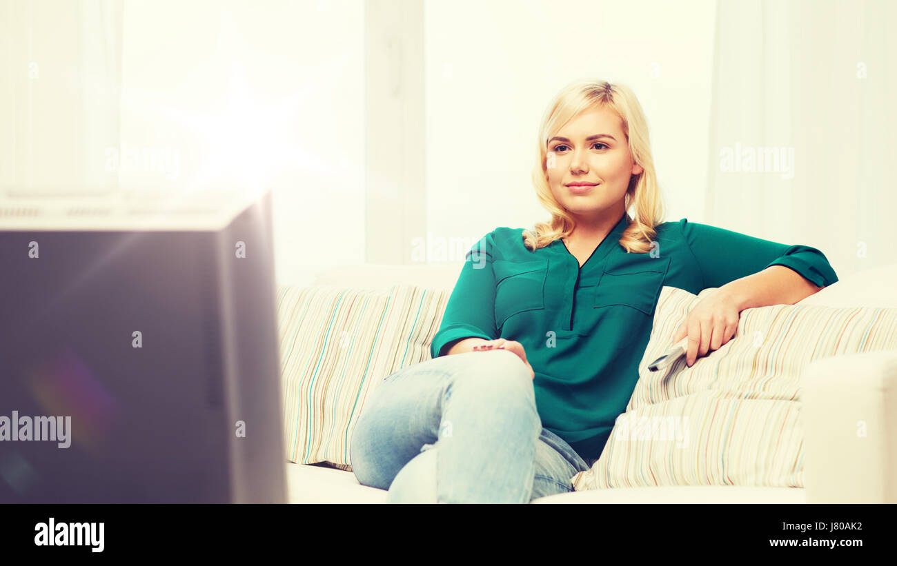 smiling woman with remote watching tv at home Stock Photo - Alamy