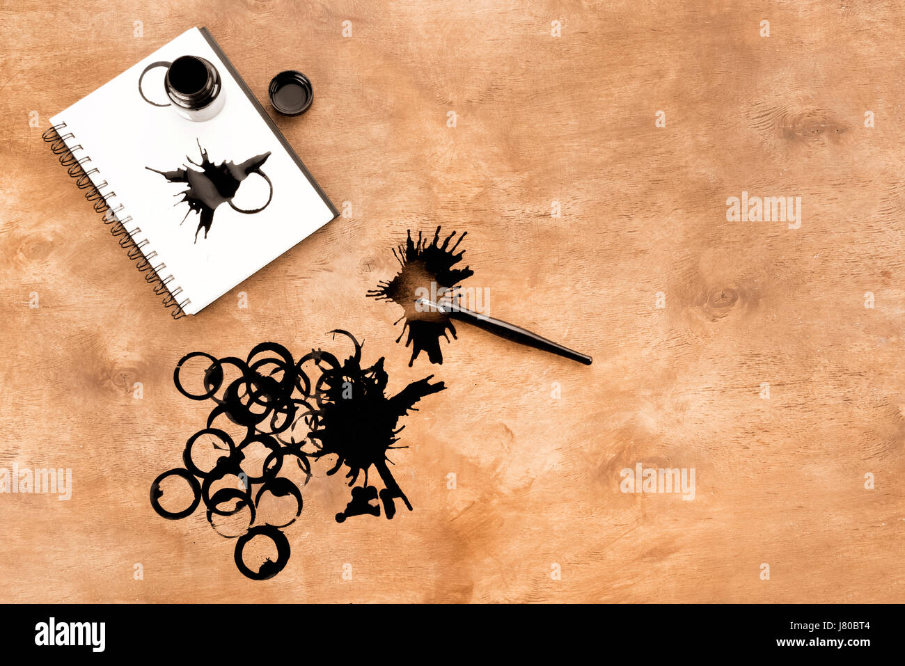 Top view of ink container, fountain pen, notebook and ink splashes on ...
