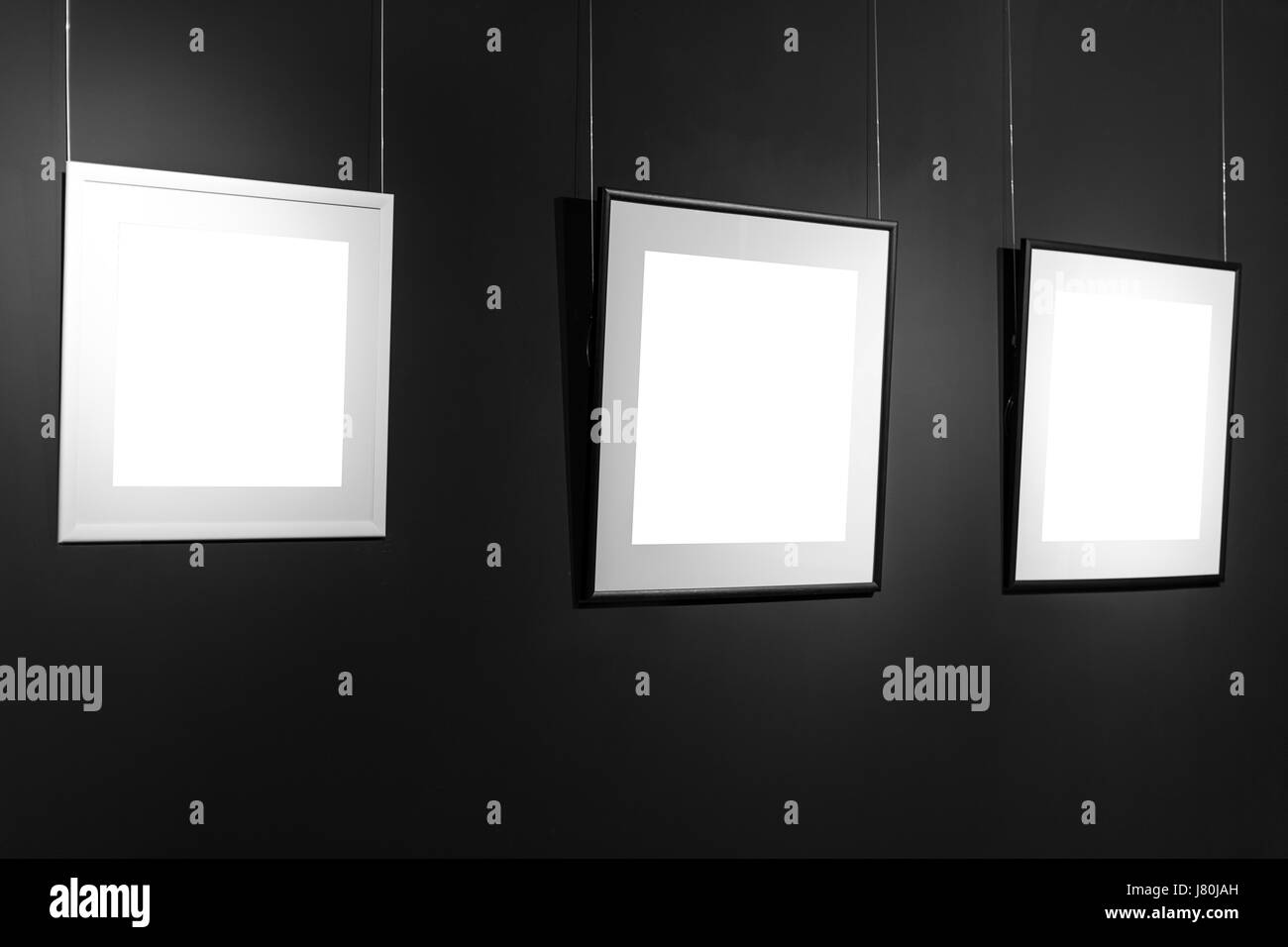 Three empty frames on black wall. Blank space posters or art frame ...