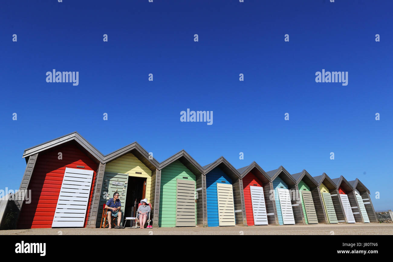 People enjoy the sunshine outside their beach hut on Blyth Beach in ...