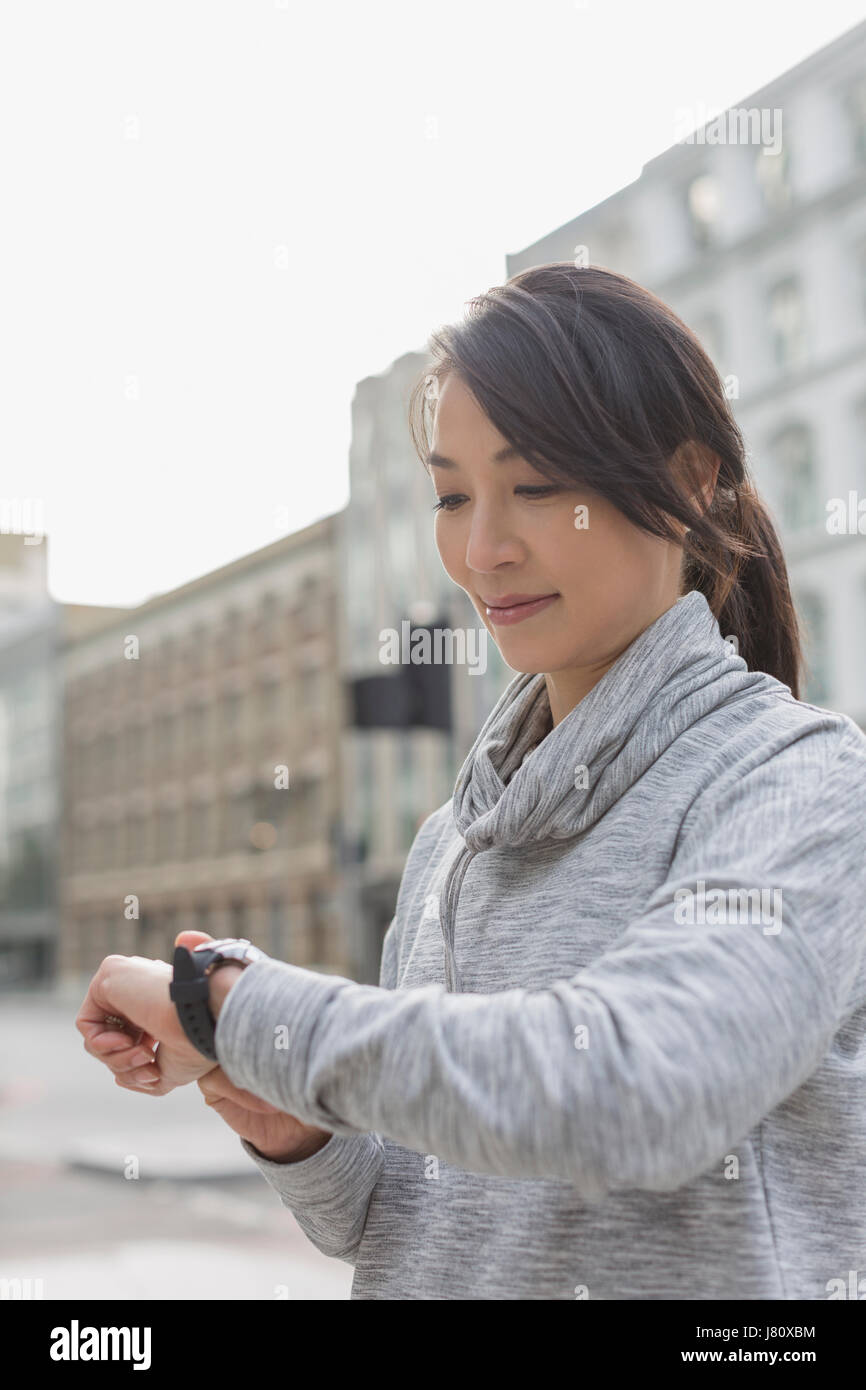 Female runner checking smart watch on urban street Stock Photo - Alamy