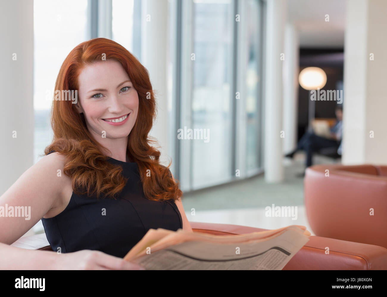 Portrait smiling businesswoman with red hair reading newspaper in ...