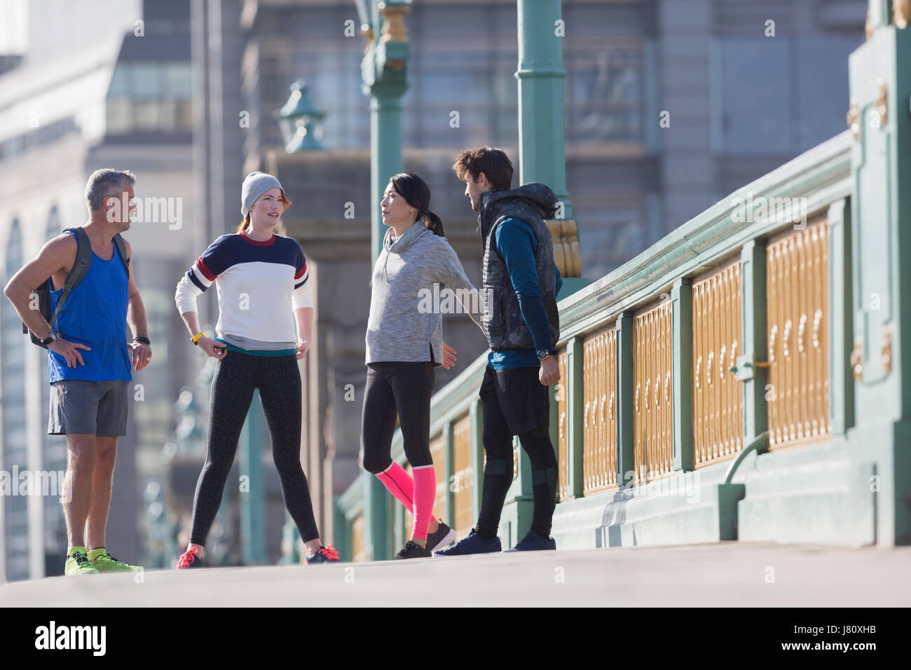 Runners talking and stretching on sunny urban sidewalk Stock Photo - Alamy