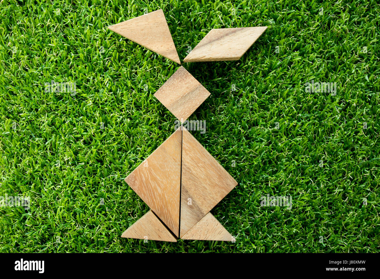 Wooden tangram puzzle in rabbit shape on artificial green grass ...