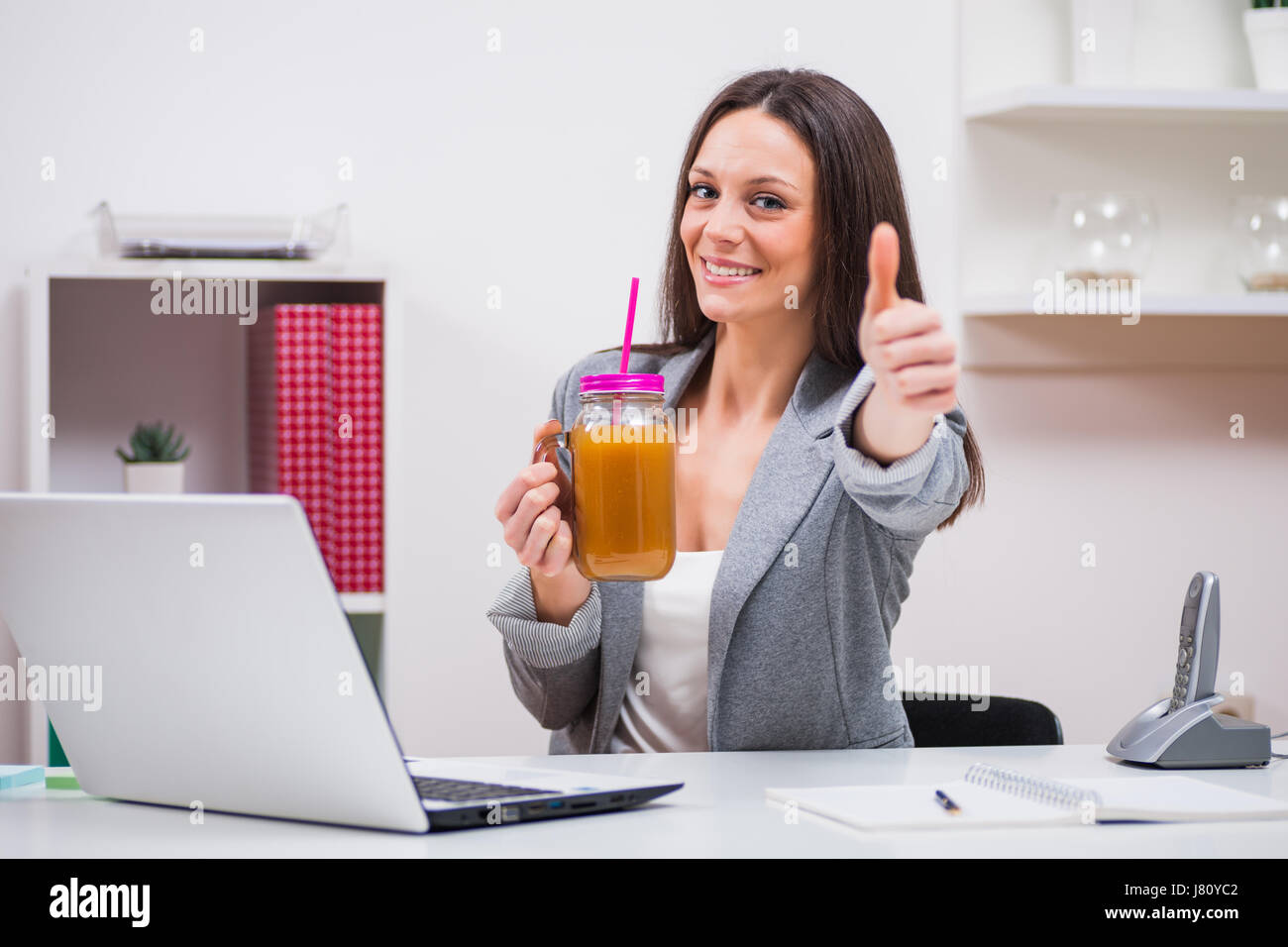 Young businesswoman is drinking smoothie in her office Stock Photo - Alamy