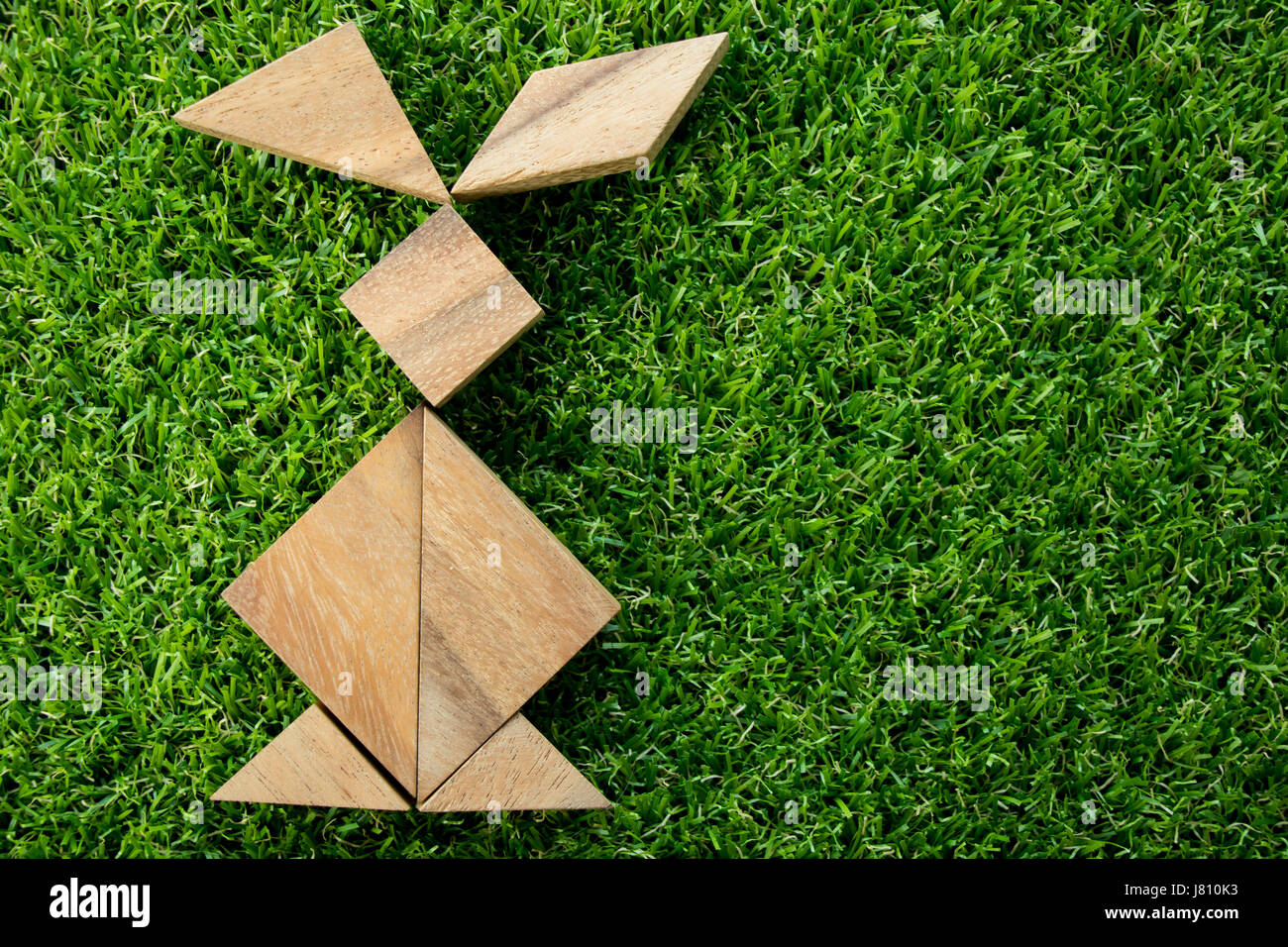 Wooden tangram puzzle in rabbit shape on artificial green grass ...