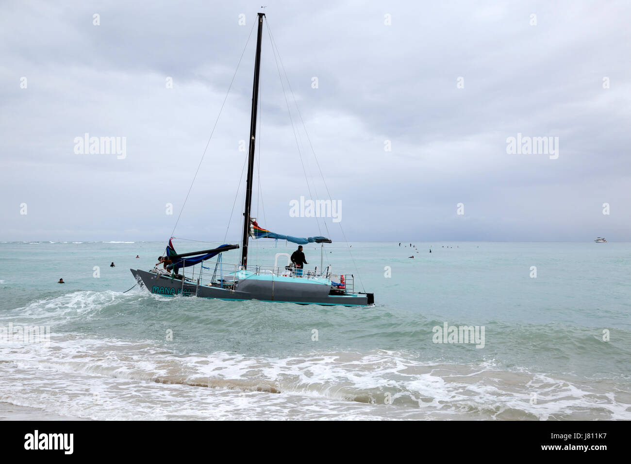 Sailing with sail down on a cloudy day. Off the coast of Waikiki in ...