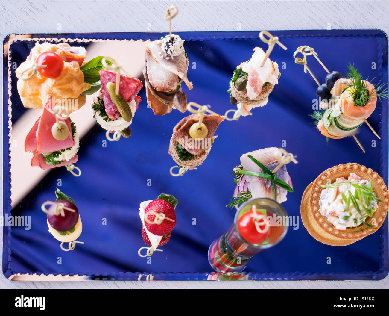 Set of different canapes and snacks served on a platter with a mirror ...