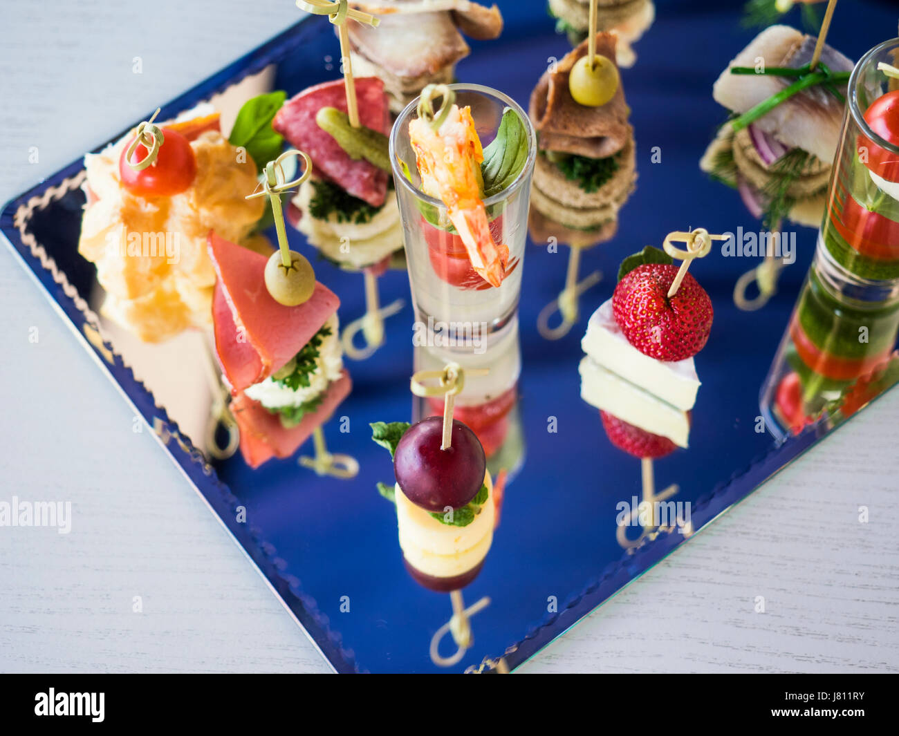 Set of different canapes and snacks served on a platter with a mirror ...