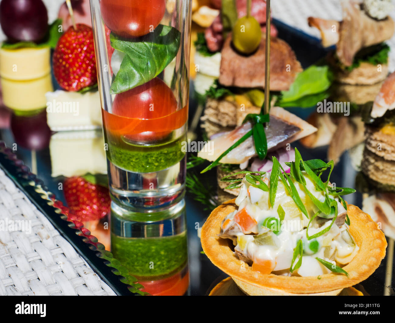 Set of different canapes and snacks served on a platter with a mirror ...