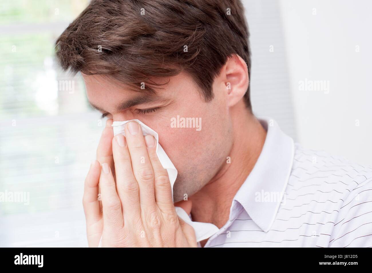 Man blowing nose on tissue Stock Photo - Alamy