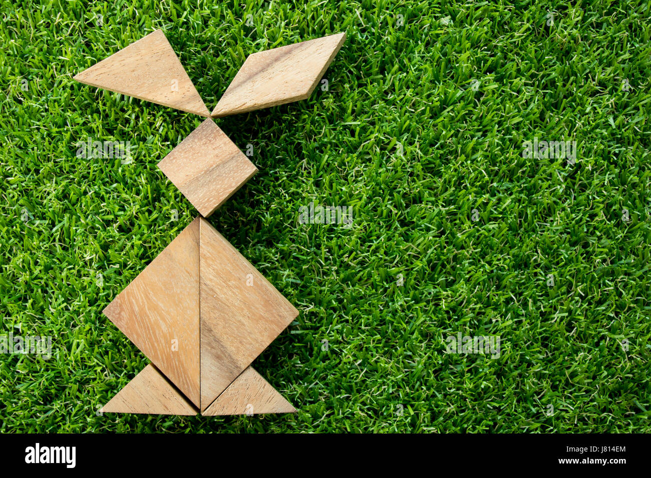 Wooden tangram puzzle in rabbit shape on artificial green grass ...