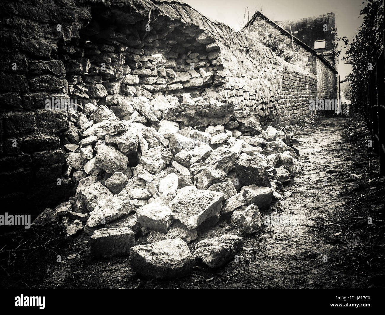 A fallen down stone wall on a path in Lower Heyford, Oxfordshire. April ...