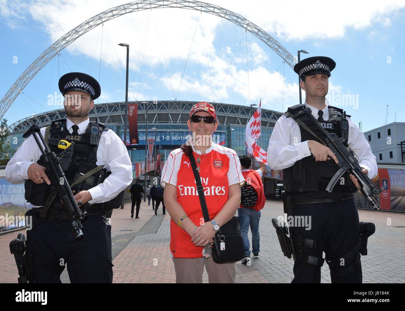 An Arsenal fan poses for a photograph between armed police officers as ...