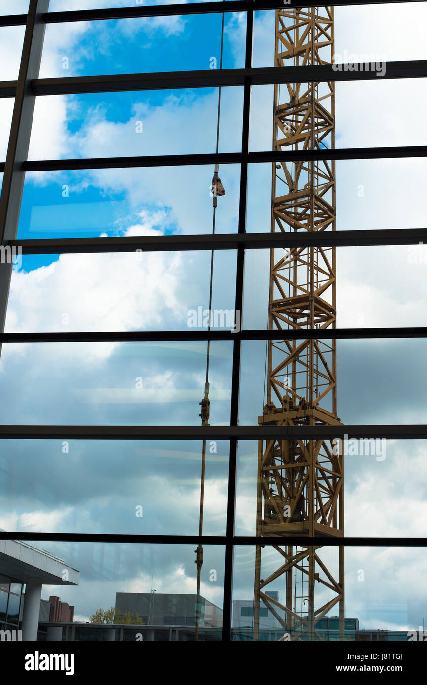 Construction crane behind a window front against blue sky with clouds ...