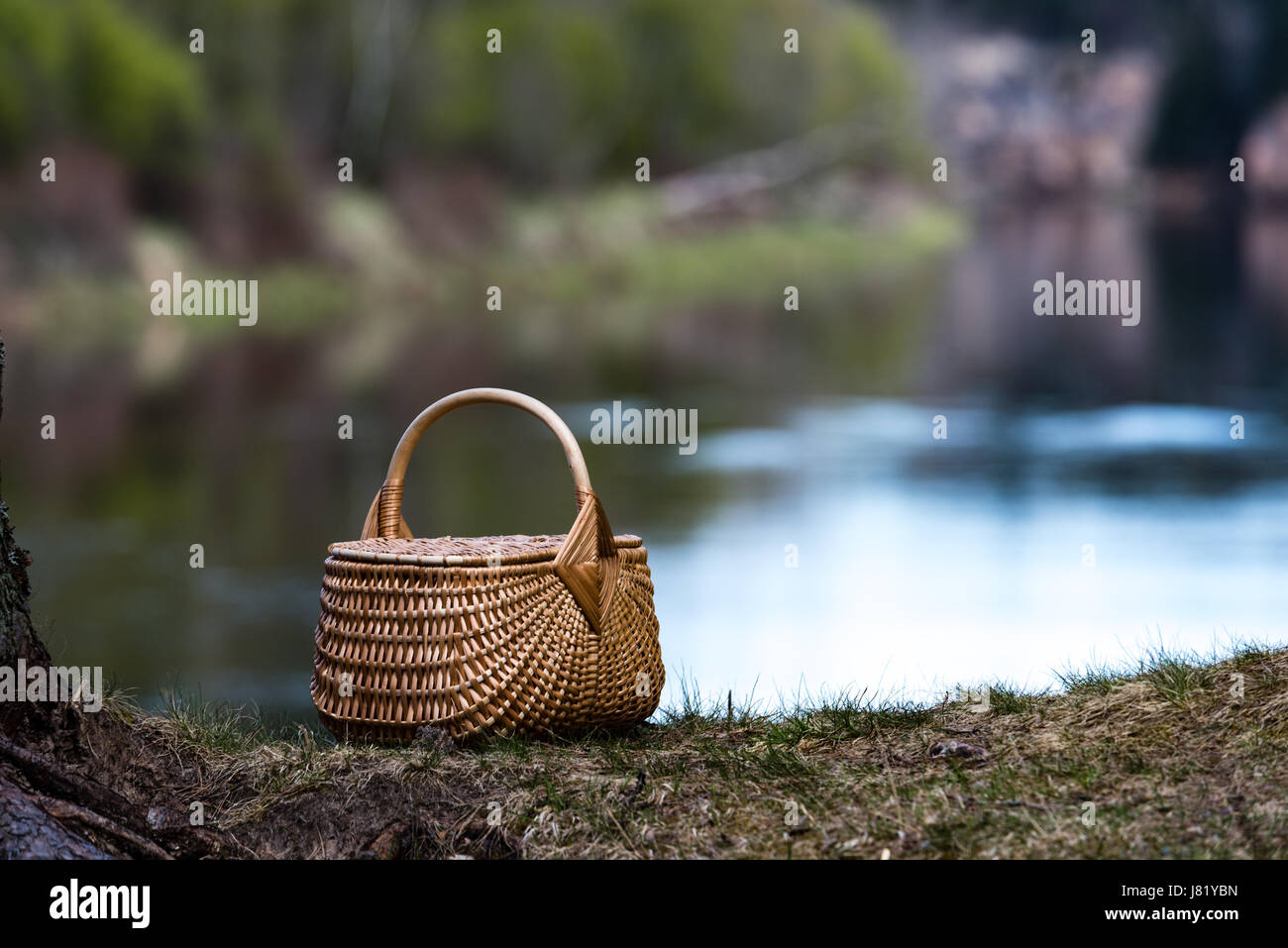 beautiful wooden woven basket in front of forest river with blur ...
