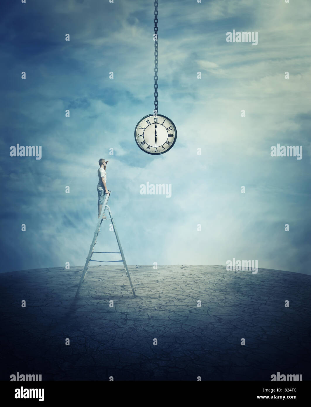 Young boy stay on the top of a ladder in the middle of a cracked desert ...