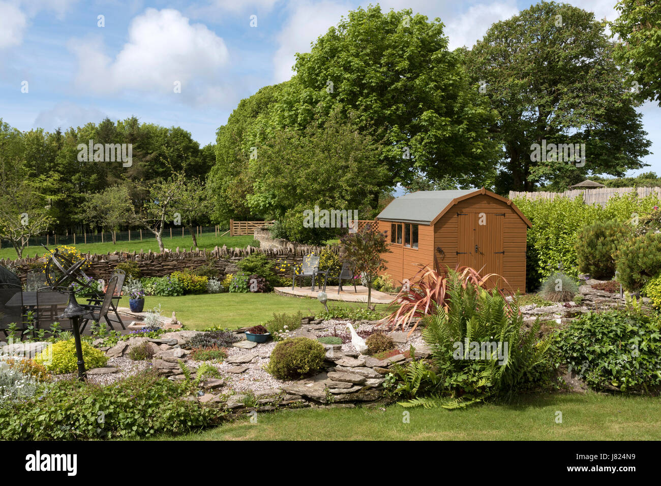 A Dutch barn style garden shed with a patio in a English country garden ...