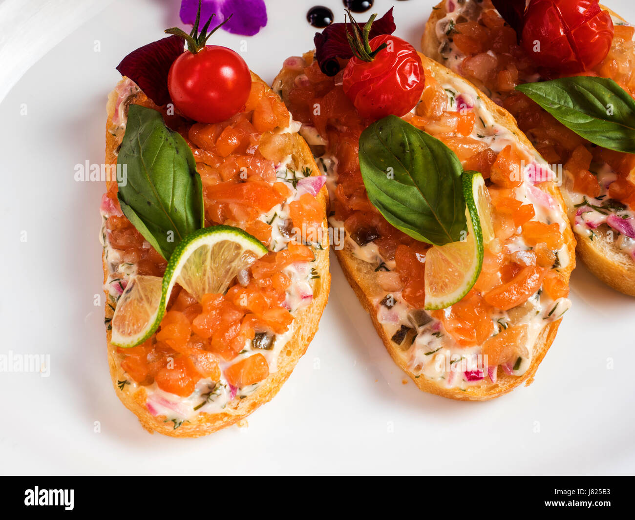 Bruschetta with cream cheese, red light-salted fish, baked tomatoes and ...