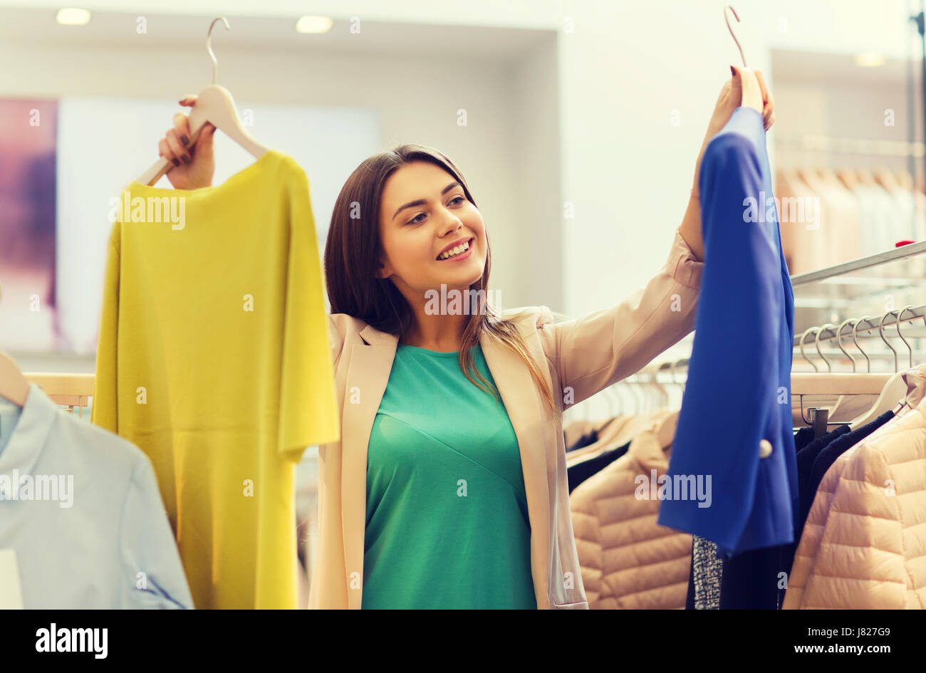 happy young woman choosing clothes in mall Stock Photo - Alamy